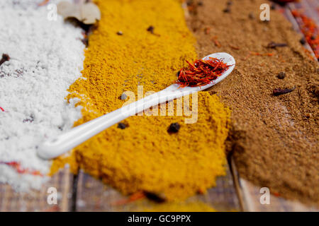 White spoon with shafran on different colorful spices background ...
