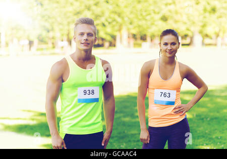 happy friends or couple with racing badge numbers Stock Photo - Alamy