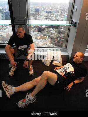 From above of male runner sitting on stone border and stretching legs ...