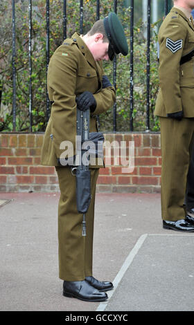 Armed with a rifle, a British soldier stands guard atop a wall ...