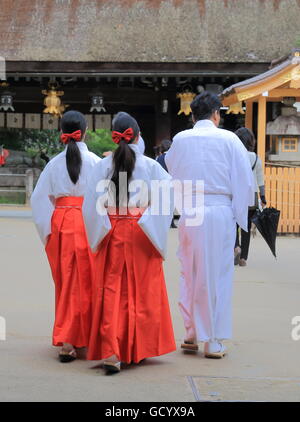 Miko shrine maiden in traditional shinto costume at Shimon main gate ...