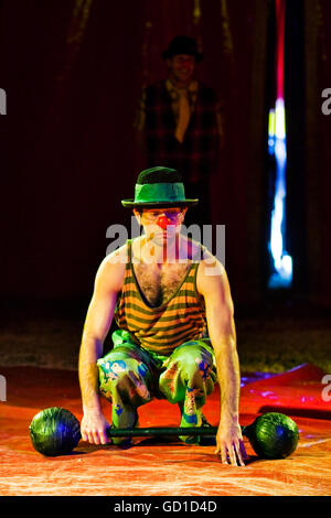 Full body of male circus artist in red trousers and hat performing ...