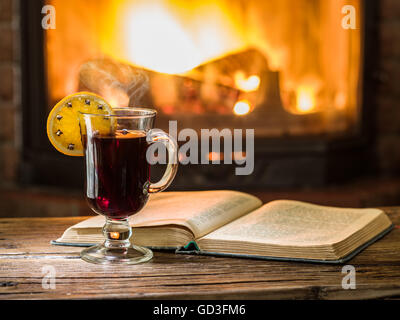 Glass of wine and book by fireplace Stock Photo - Alamy
