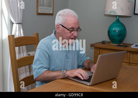Old man sat down at a table using a laptop computer Stock Photo - Alamy