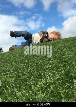 boy child rolling down a grass hill or lawn Stock Photo - Alamy