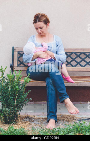Cheerful young mother breastfeeding infant in public, Woman and new mom ...