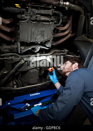 Mechanic inspecting under a car Stock Photo - Alamy