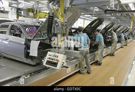 BMW 1 and 3 Series on an assembly line move past office-workers at the ...