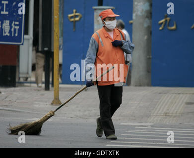BEIJING CHINA Street sweeper in orange work wear walks on the street ...