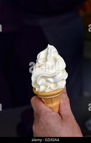 Hand holding vanilla ice cream cone blue background Stock Photo - Alamy