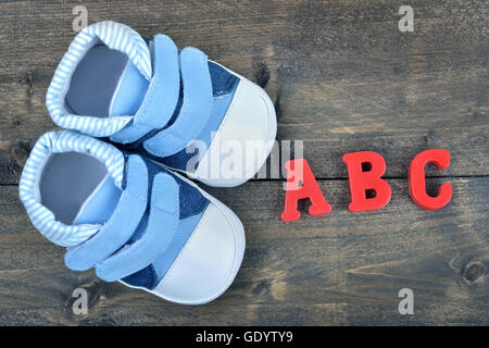 Kid shoes and word ABC on wooden table Stock Photo - Alamy