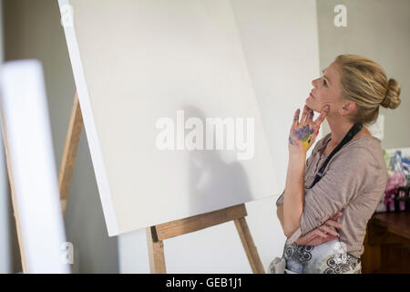 Woman observing canvas before setting up artwork at home studio Stock ...
