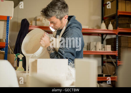 Worker pouring gypsum plaster in open form for mold casting for making ...