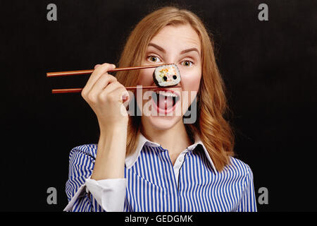 fun girl show snout with sushi roll on black background with copyspace ...