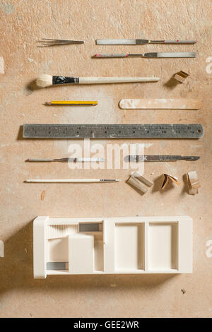 A plaster scale model building alongside tools for arts and crafts ...