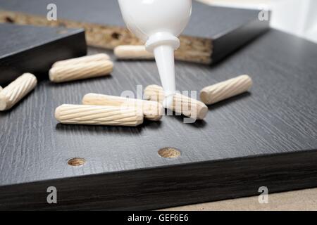 inserting glue to the hole on black particleboard Stock Photo - Alamy