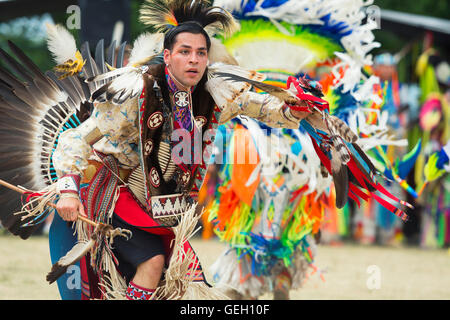 Canadian native in traditional dress singing and playing the typical ...