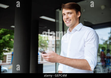 Young urban man with smarphone outdoors on the background of famous ...