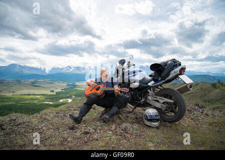 bald motorcyclist plays guitar sitting on a motorcycle the ba Stock ...