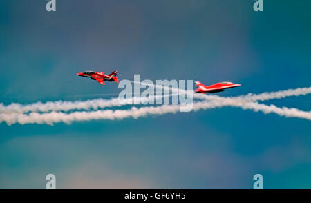 Two RAF Red Arrows perform an acrobatic maneuver in formation with ...