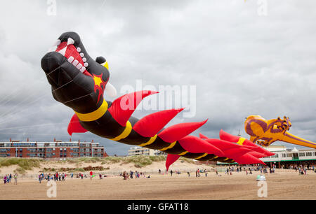 Colorful kites in the shape of dragons flying above the dunes of the ...