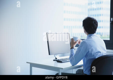 Rear view of businessman relaxing in creative office space Stock Photo ...