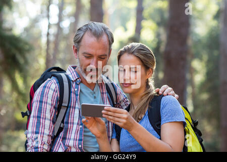 Female hiker using mobile phone while standing on mountain against blue ...