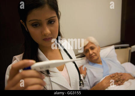 Indian female doctor checking temperature in digital thermometer Stock ...