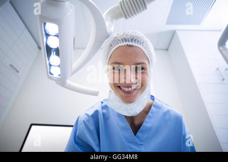 Dental assistant smiling at camera beside light Stock Photo - Alamy