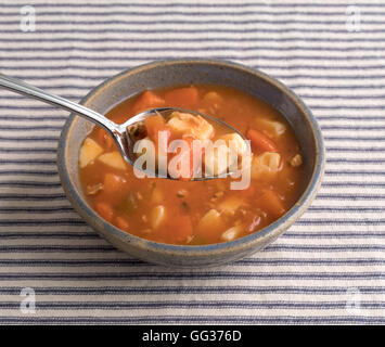 A portion of Manhattan style clam chowder on a large black kitchen ...