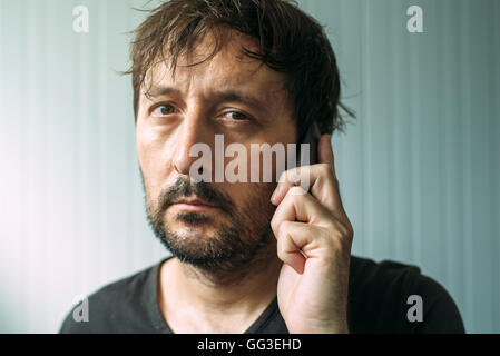 Portrait of tired sleepy man talking on mobile phone with friend making ...