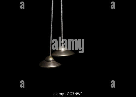 Hindu cymbals hanging from a white rope on black background Stock Photo ...