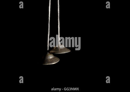 Hindu cymbals hanging from a white rope on black background Stock Photo ...