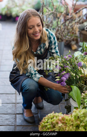 Smiling florist looking at the plant on the porch Stock Photo - Alamy