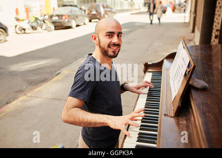Young hispanic man playing piano at music studio smiling with happy ...