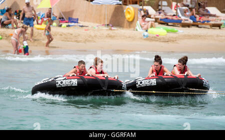inflatable ride pulled along by speedboat beach fun Stock Photo - Alamy