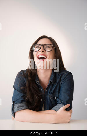 Happy woman wearing eyeglasses leaning on glass door Stock Photo - Alamy