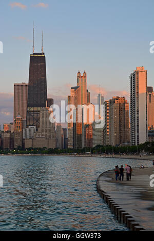 A cityscape on the side of a lake with skyscrapers, during the evening ...