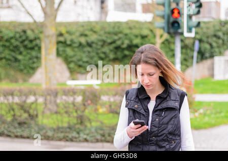 Young woman checking messages on the cell phone, inside a coworkin ...