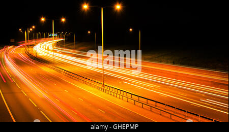 The M25 motorway at night. A long exposure shows the flow of traffic ...