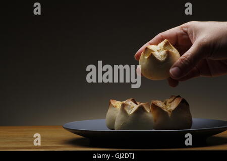 Hand getting a freshly baked Filipino sweet bread called "pan-de-regla ...