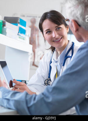 Male doctor with tablet and patient on light background Stock Photo - Alamy