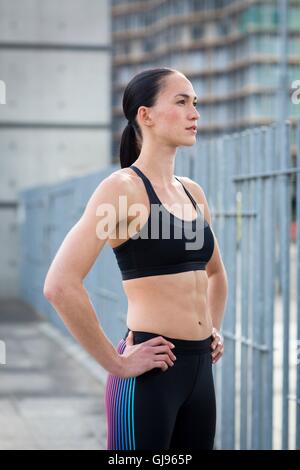 young woman in crop top and trendy sunglasses in green light isolated ...