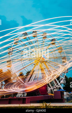 Rotating illuminated attraction in amusement park at night. Motion ...