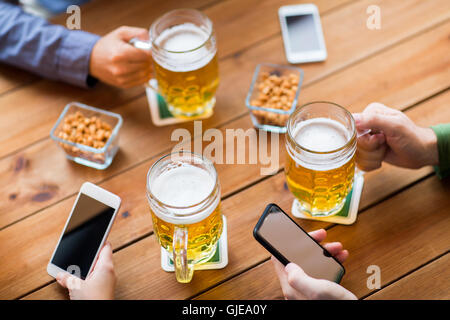 close up of hands with smartphones and beer at bar Stock Photo - Alamy