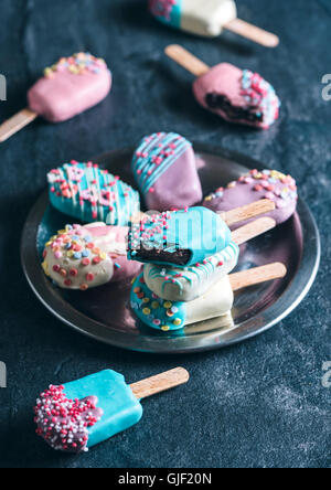A cake pop in the shape of an ice lolly with brightly coloured icing on ...