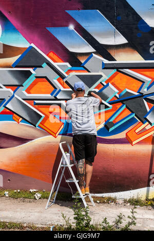 Graffiti artists hard at work painting an old wall, Friedrichshain ...