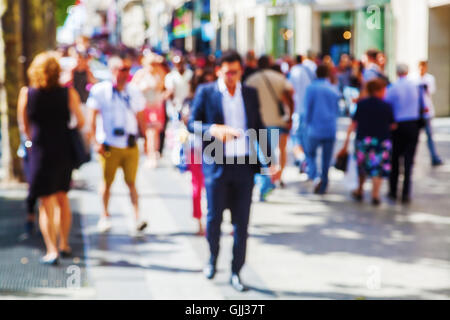 out of focus picture of a crowd of people with umbrellas crossing a ...