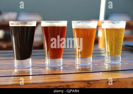 A selection of four craft beers during a tasting session on a wooden ...