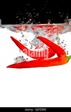 Red peppers drops in glass jar on the wooden background Stock Photo - Alamy